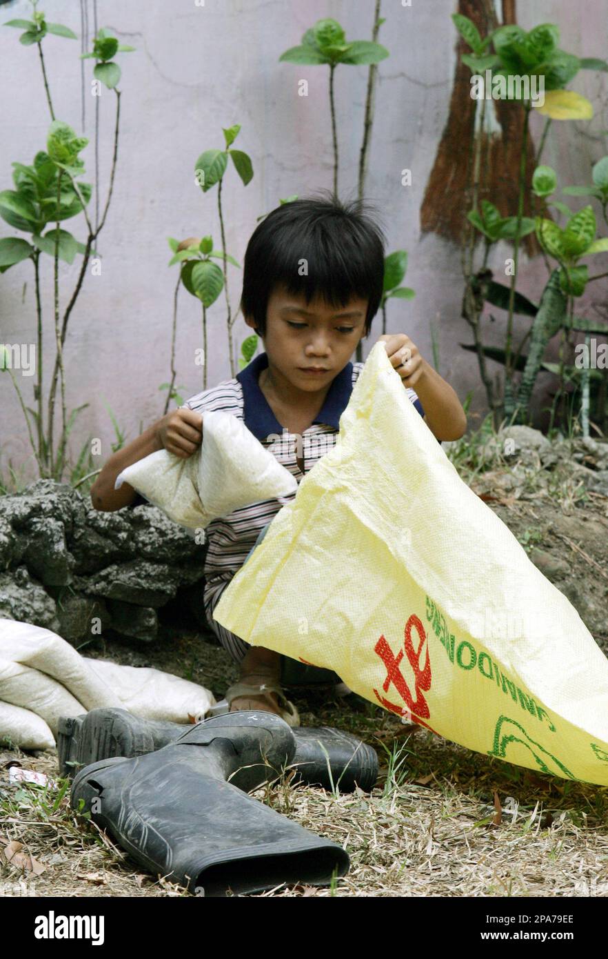 A boy places plastic bags of government-distributed U.S. rice known as ...