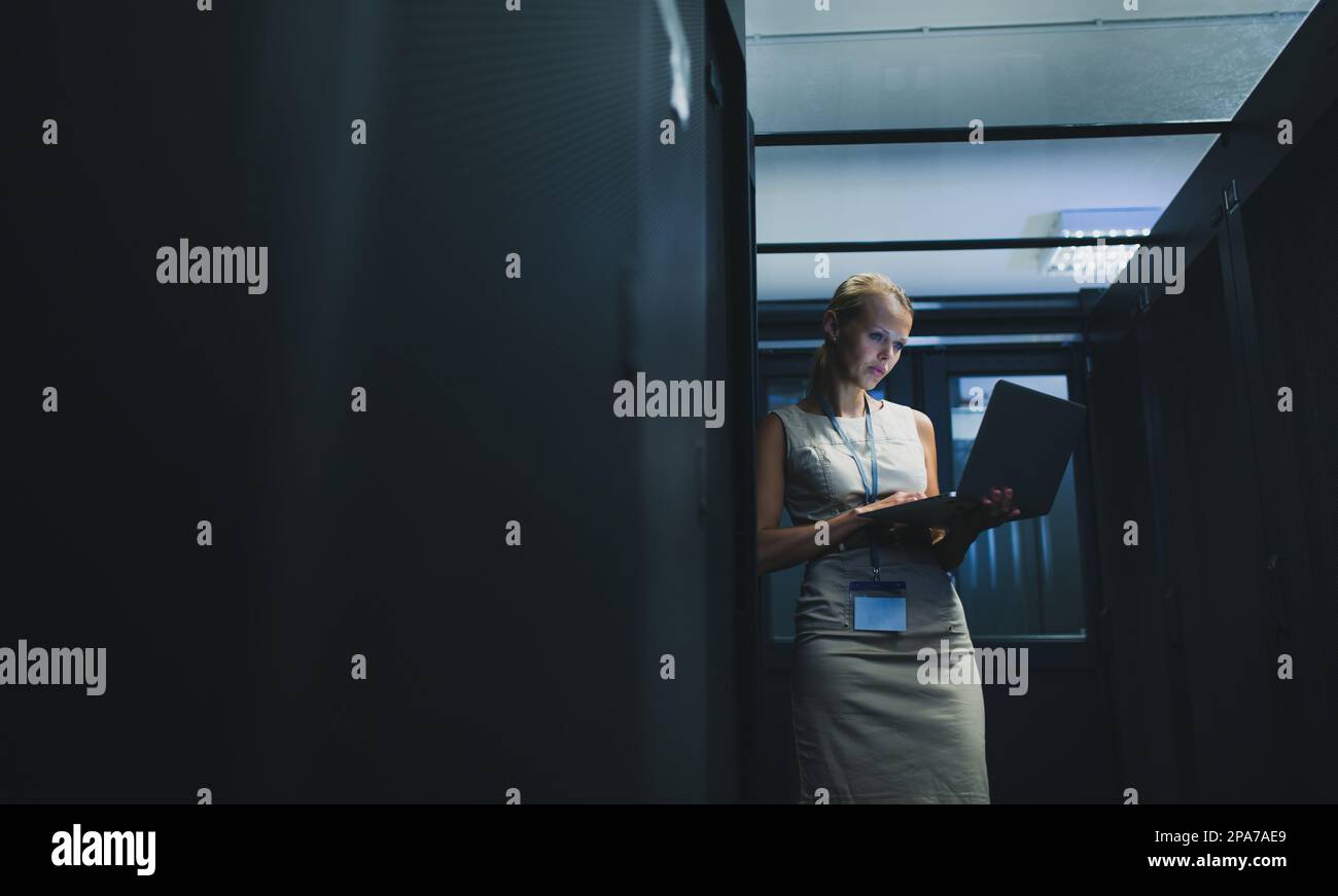IT engineer standing amid working server racks doing routine ...