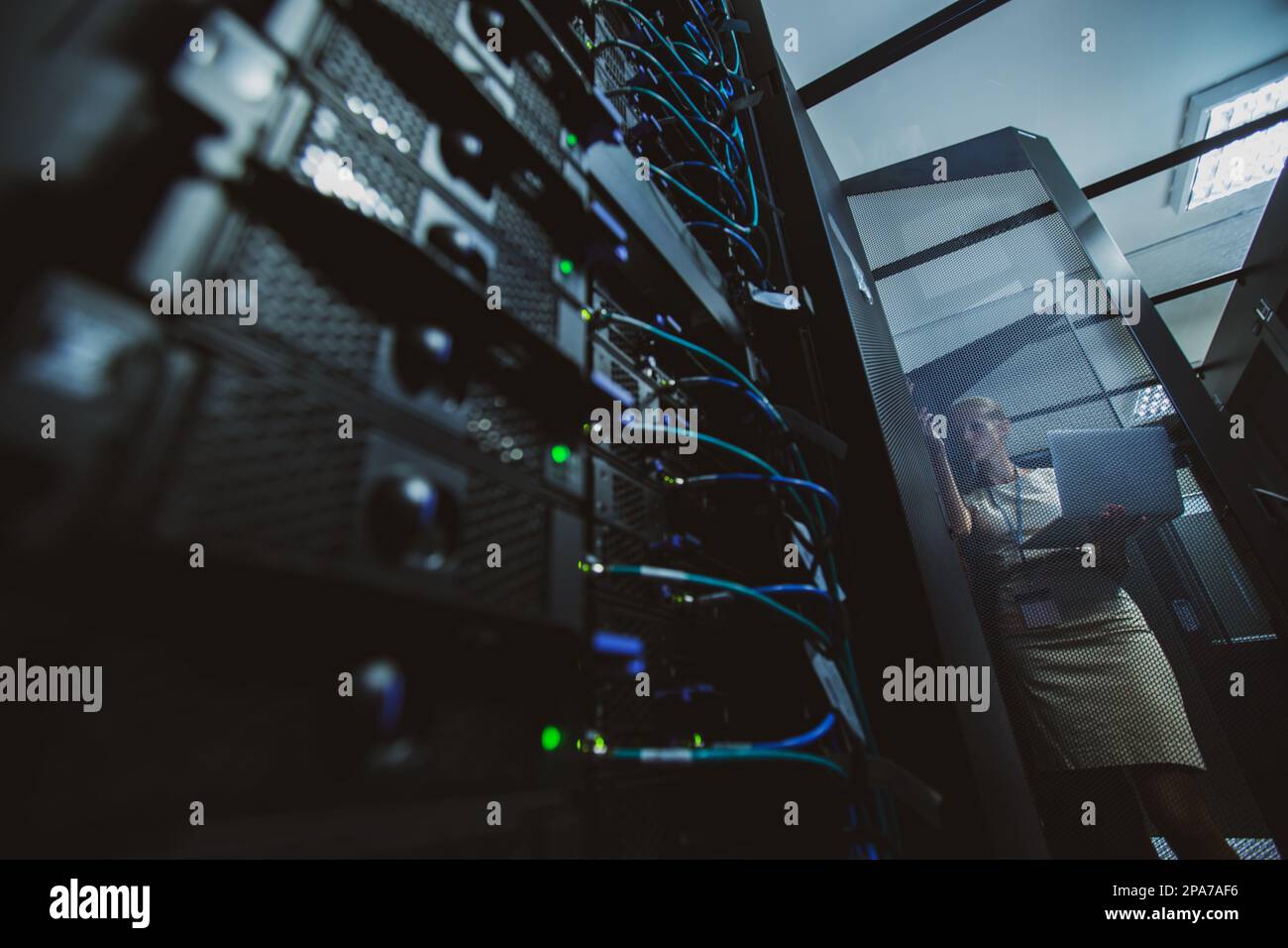 IT engineer standing amid working server racks doing routine ...