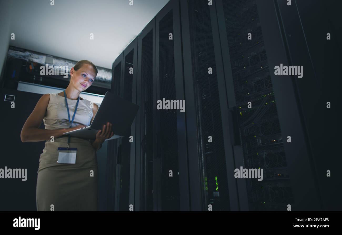 IT engineer standing before working server rack doing routine ...