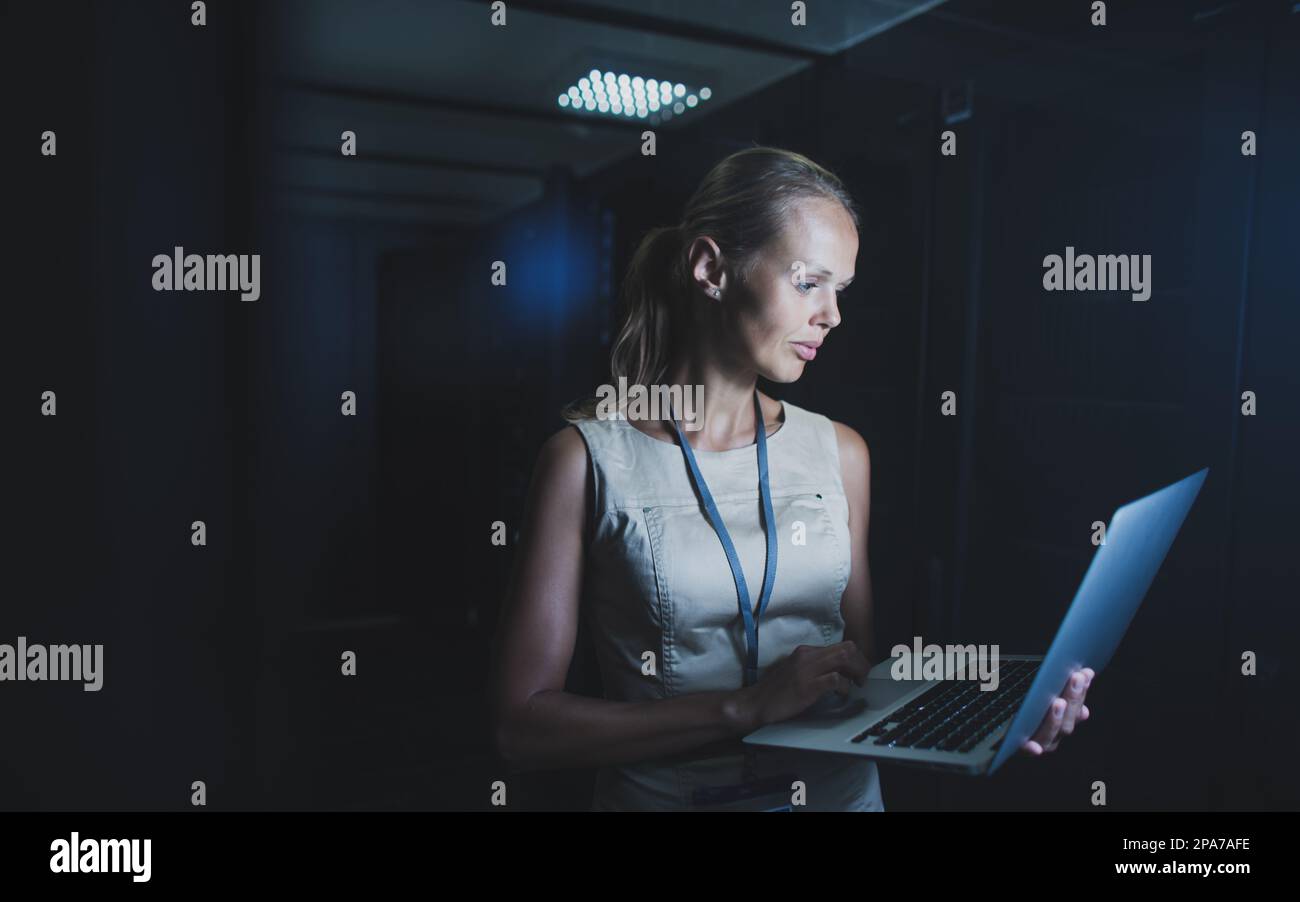 IT engineer standing before working server rack doing routine ...