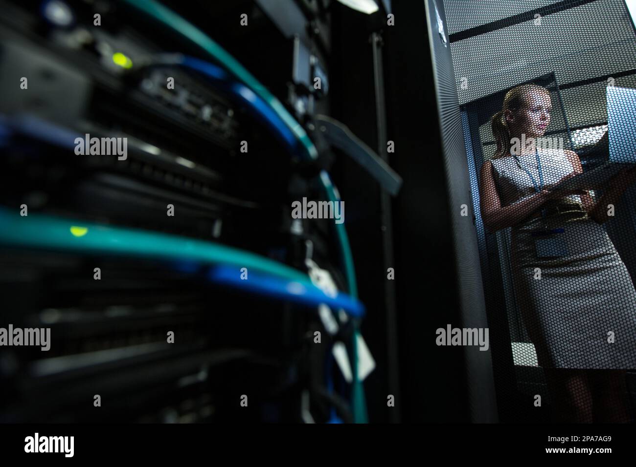 IT engineer standing amid working server racks doing routine ...