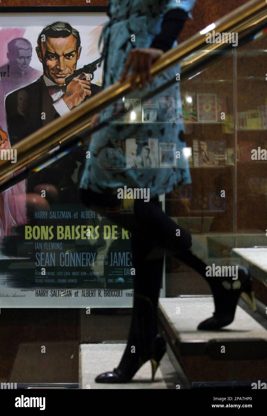 A woman poses for photographs beside a poster for a James Bond film ...