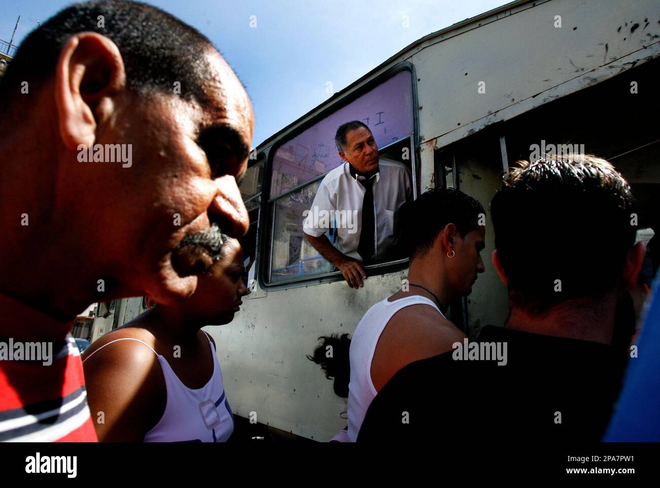 A ticket collector gets partially out of a window as Cubans get on a ...