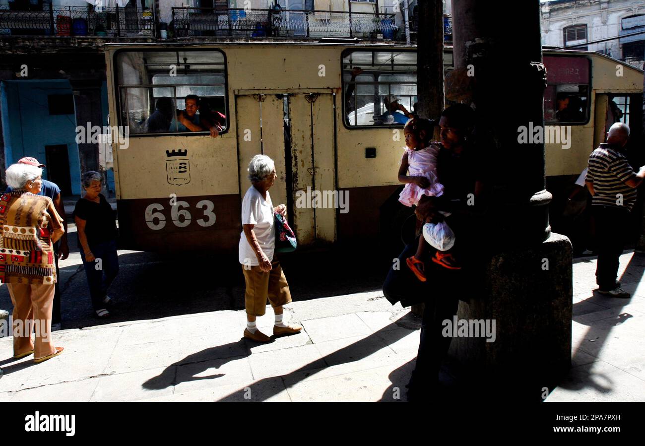 Cubans make their way next to a bus known as "camello", or camel, a ...