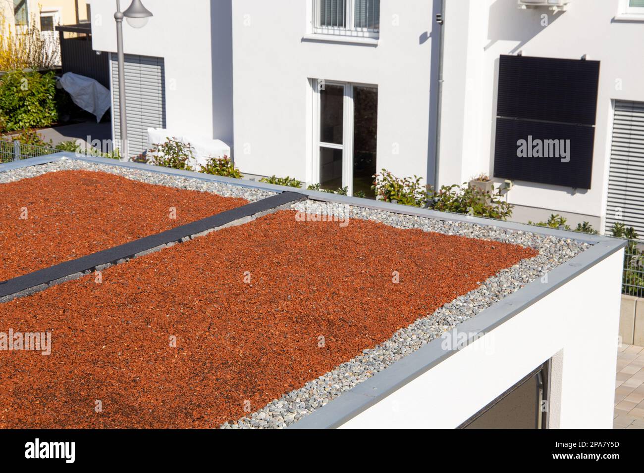 Flat roof with pebbles and red decorative stones, on which planting is ...