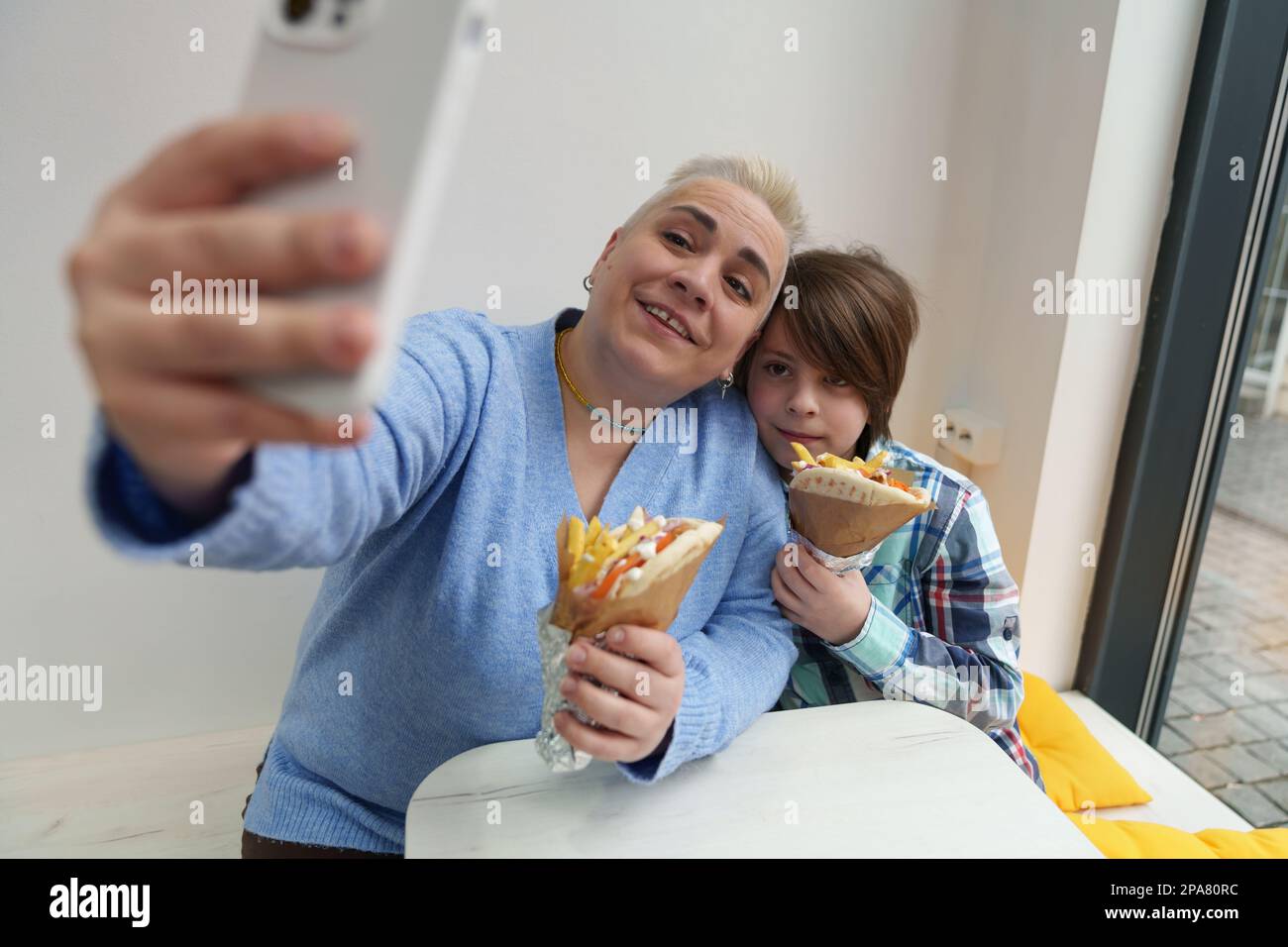 Mother takes a selfie with a smart phone while eating gyros in Greek ...