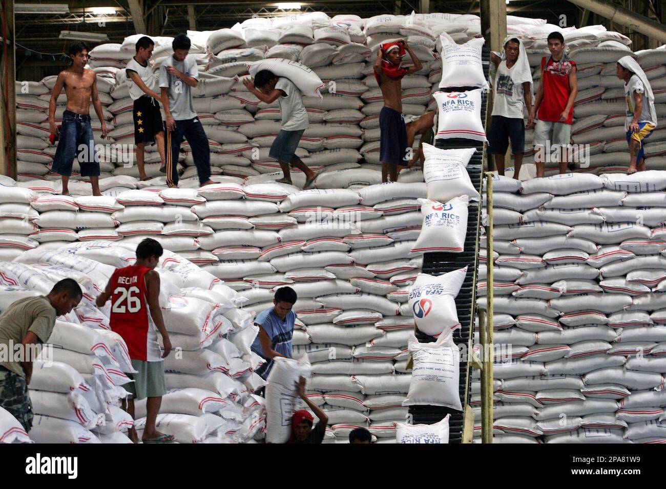 Workers stack imported rice which will be repacked and sold to poor ...