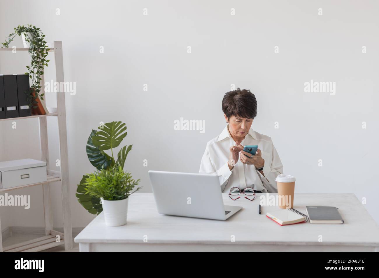 Portrait of middle aged secretary who typing sms on smartphone instead ...