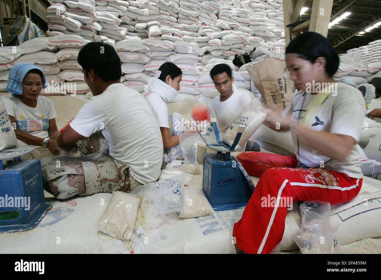Workers prepare sacks of imported rice for repacking and be sold to ...