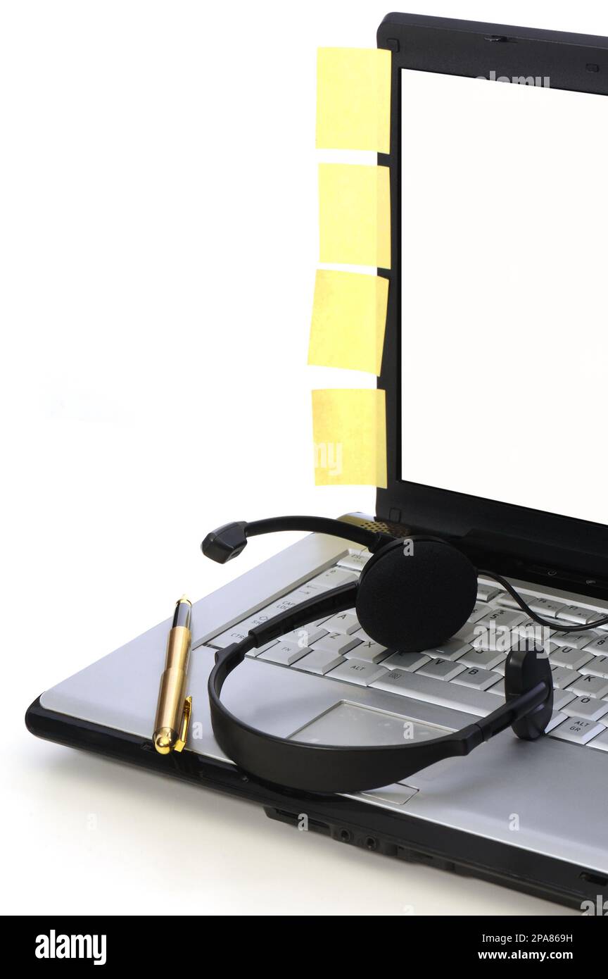 black wireless telephone on computer mouse, headphones on top of laptop ...