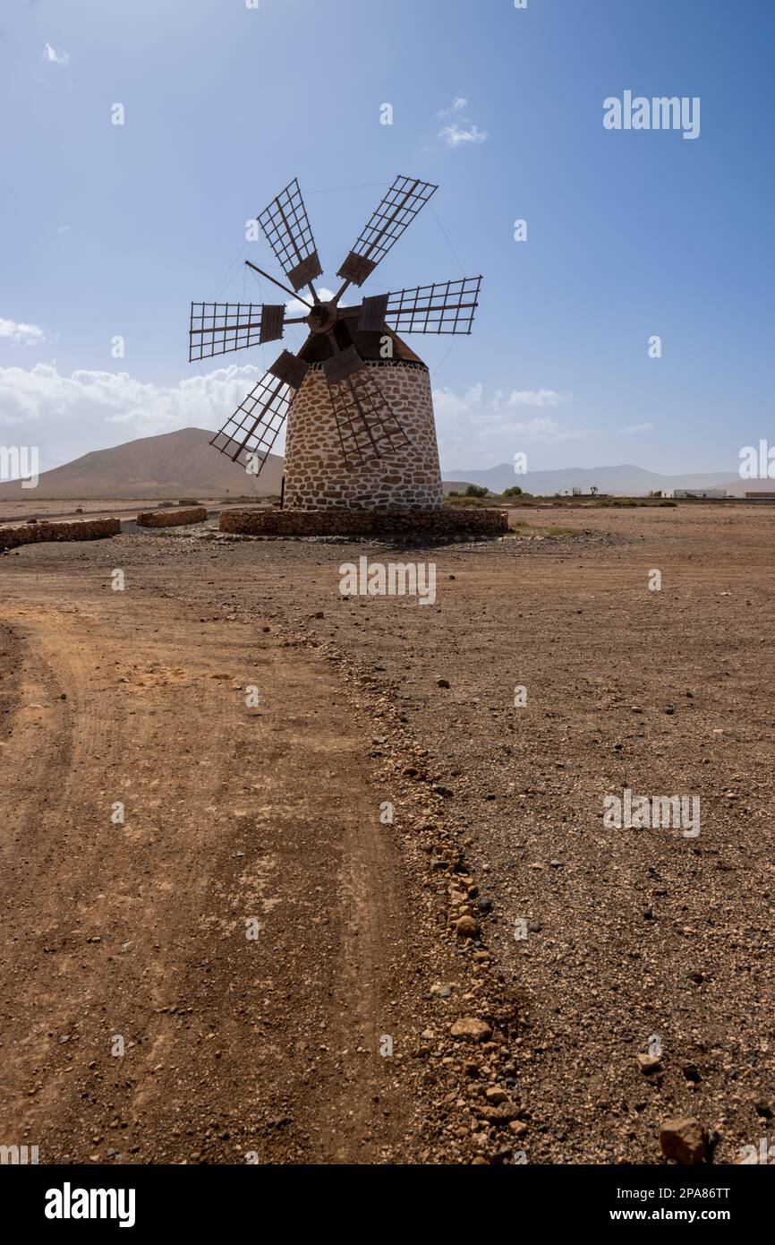 Old traditional windmill, located in a stone desert. Blue sky with some ...
