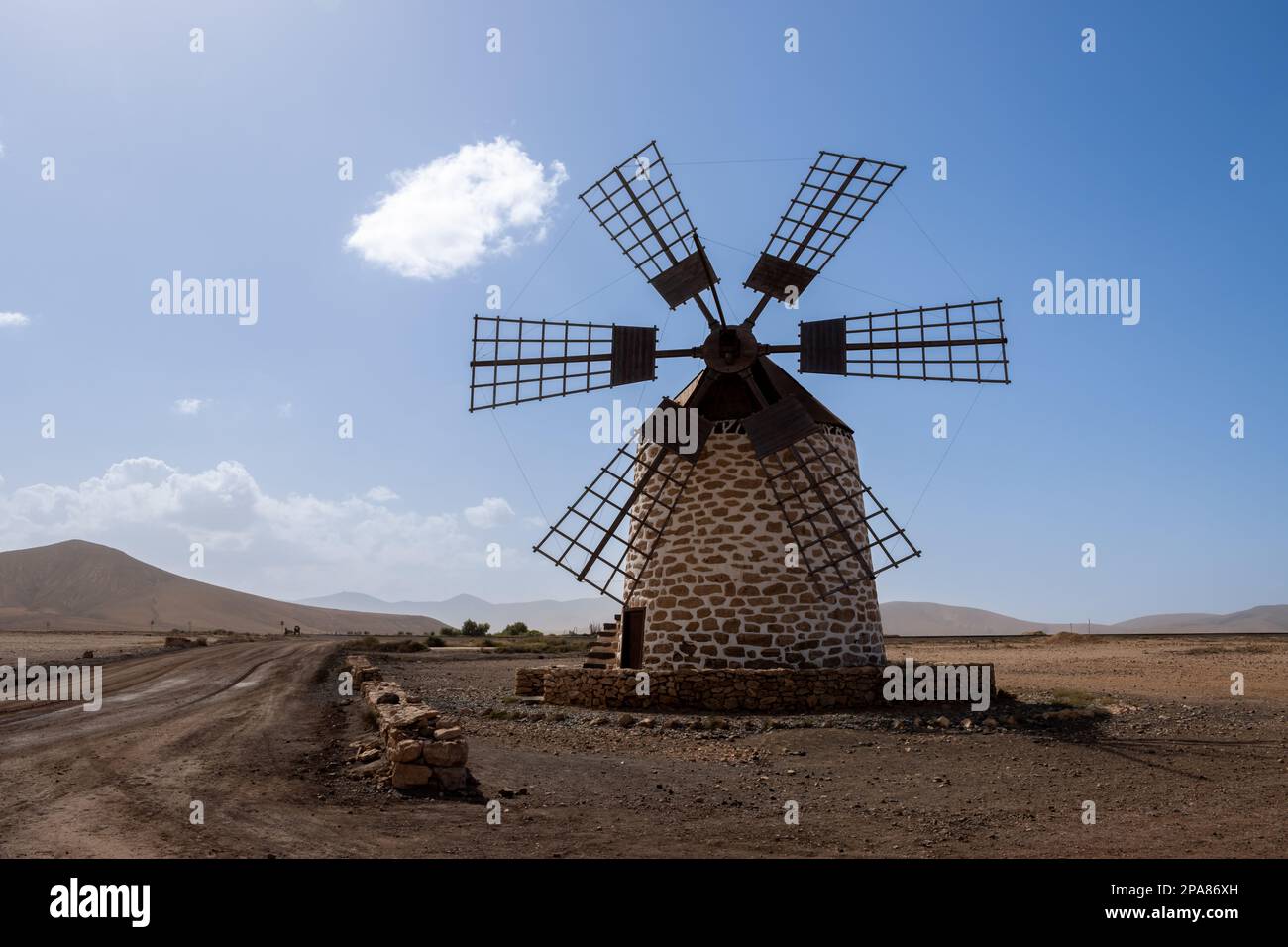 Old traditional windmill, located in a stone desert. Blue sky with some ...