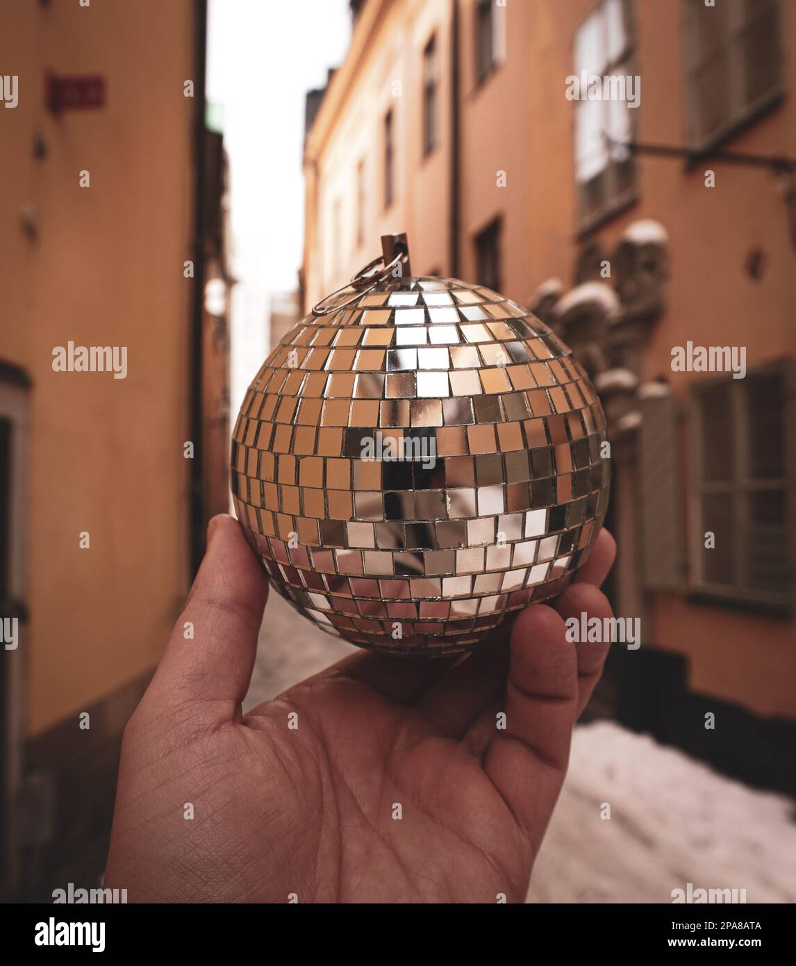 Cropped hand holding disco ball admist buildings Stock Photo - Alamy