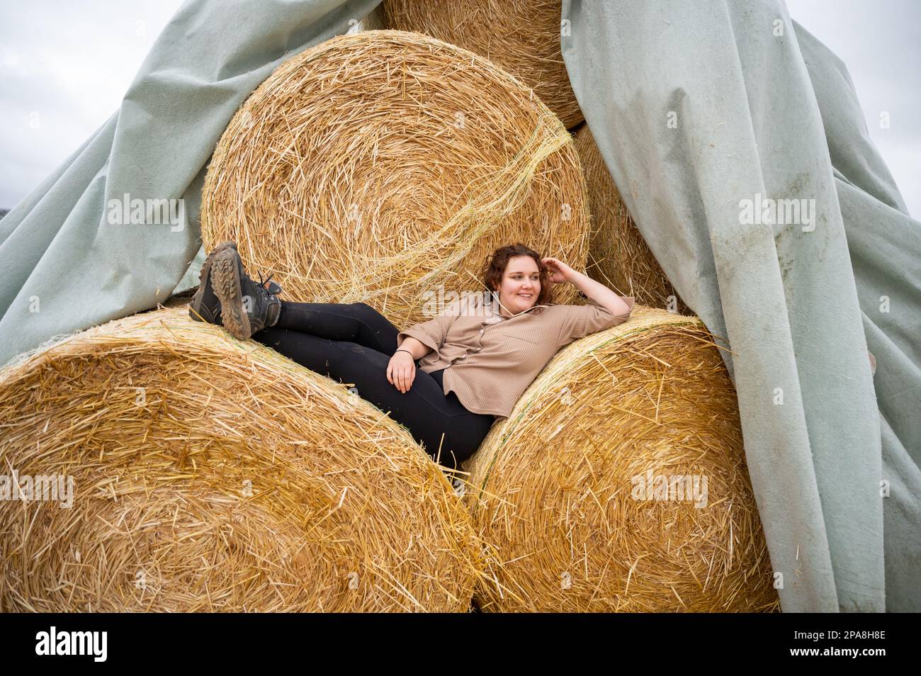 Young woman with brown curly hair is enjoying the summer, lying on two ...