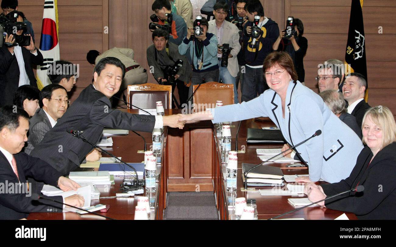 South Korean Assistant Agriculture Minister Min Dong-seok, left, shakes hands with U.S. Deputy ...