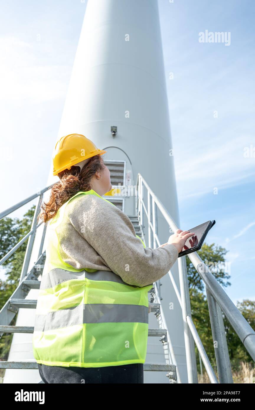 Female engineer with brown curly hair and yellow helmet using her ...