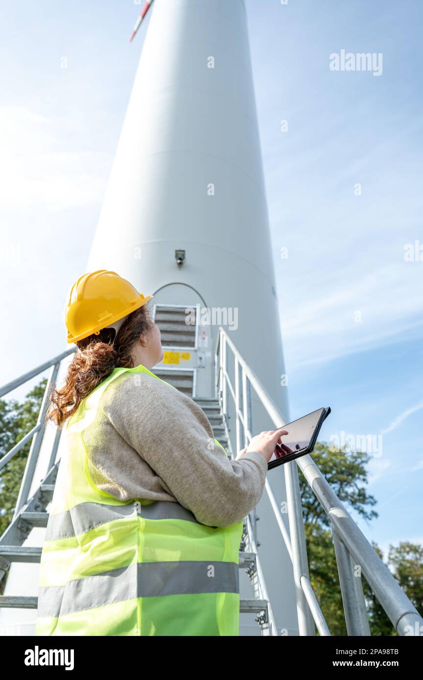 Female engineer with brown curly hair and yellow helmet using her ...