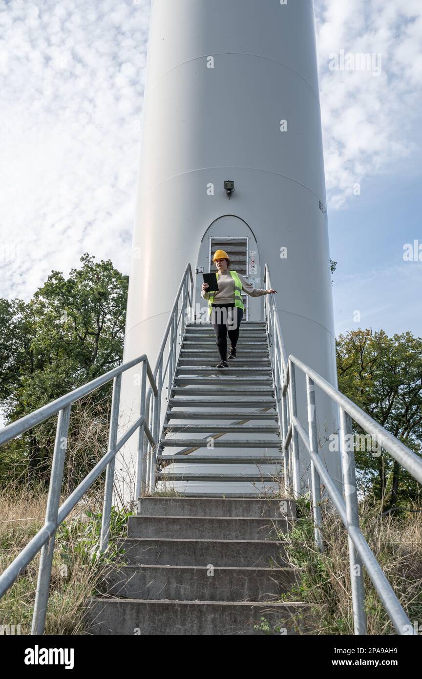 Female engineer with brown curly hair and yellow helmet using her ...