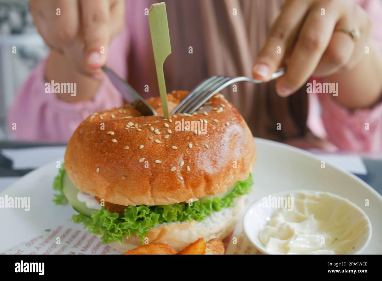 women hand with knife and fork eating a burger Stock Photo - Alamy