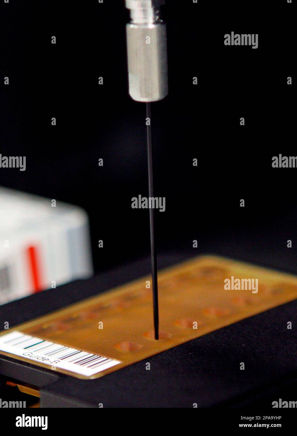 A robotic arm puts a drops of DNA-bearing solution on a slide during a ...