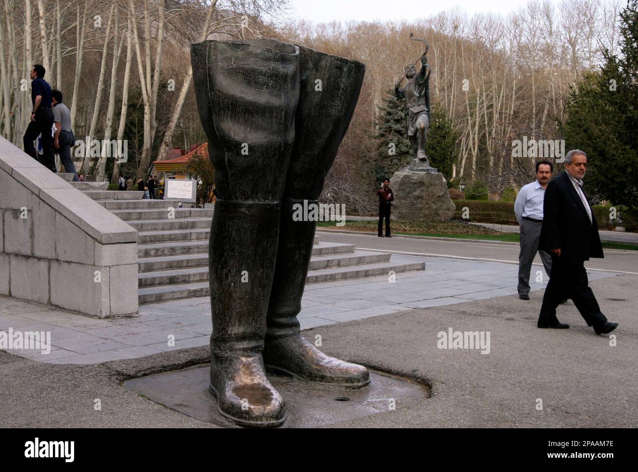 Iranian men walk past the remains of a statue in bronze of Reza Shah ...