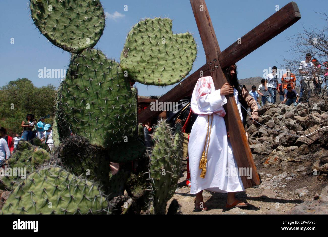 Juan Carlos Longoria, portraying Christ, carries a cross during the Via ...