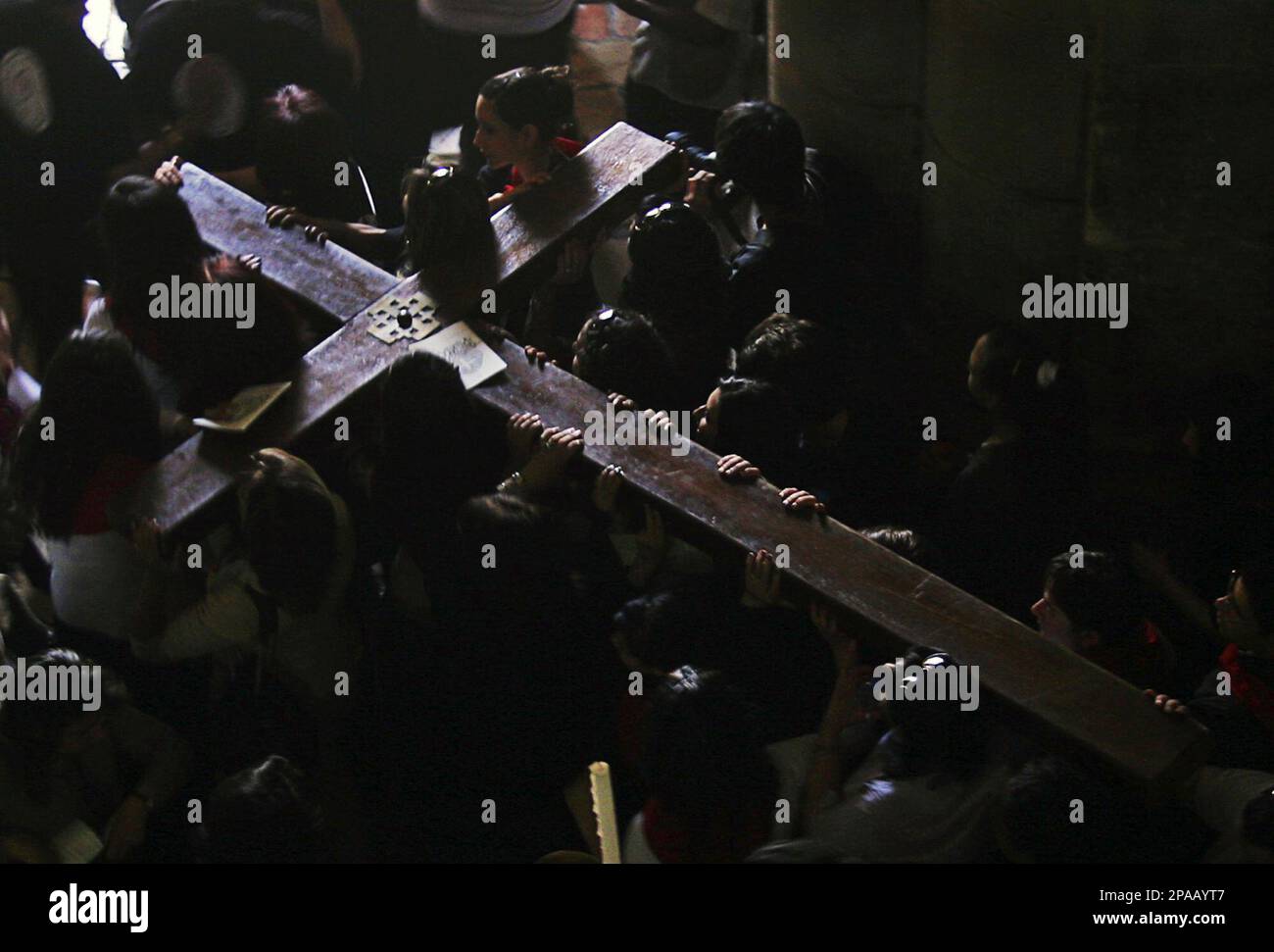 Christian worshippers carry a large wooden cross out of the Church of ...