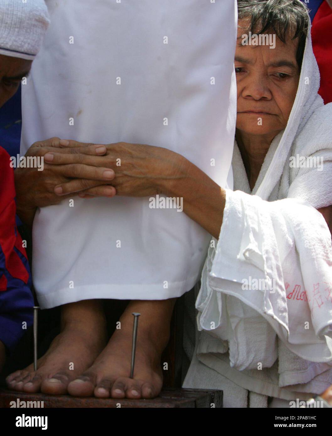An ederly woman holds the legs of Buboy Dionisio after he was nailed to ...