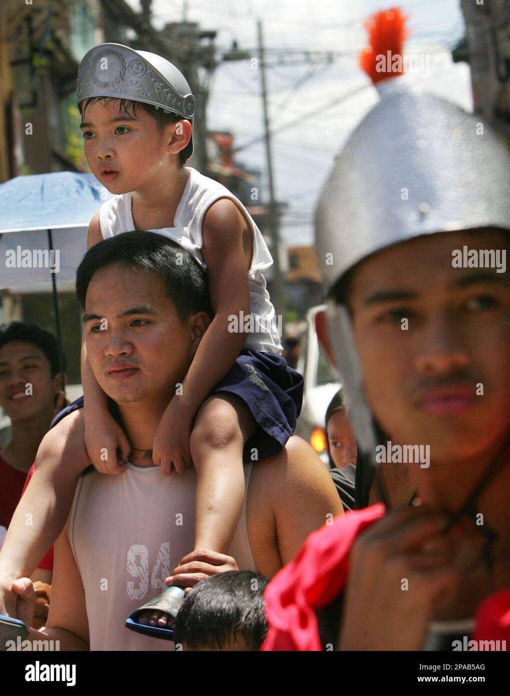 A young boy wearing a Roman soldier helmet views the reenactment of the ...