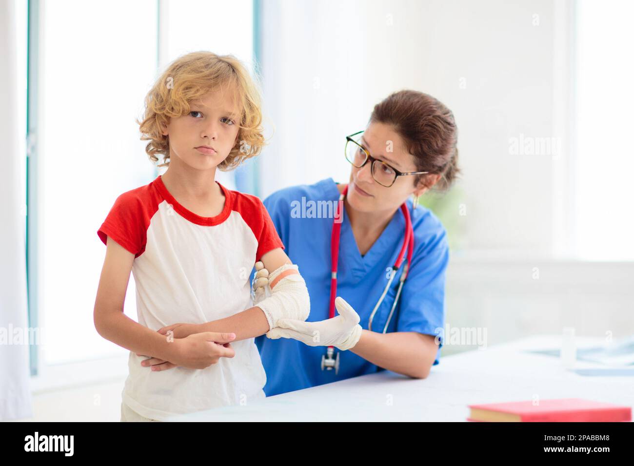 Child with arm injury at trauma and emergency care. Kid with elbow cast at health clinic. Doctor ...