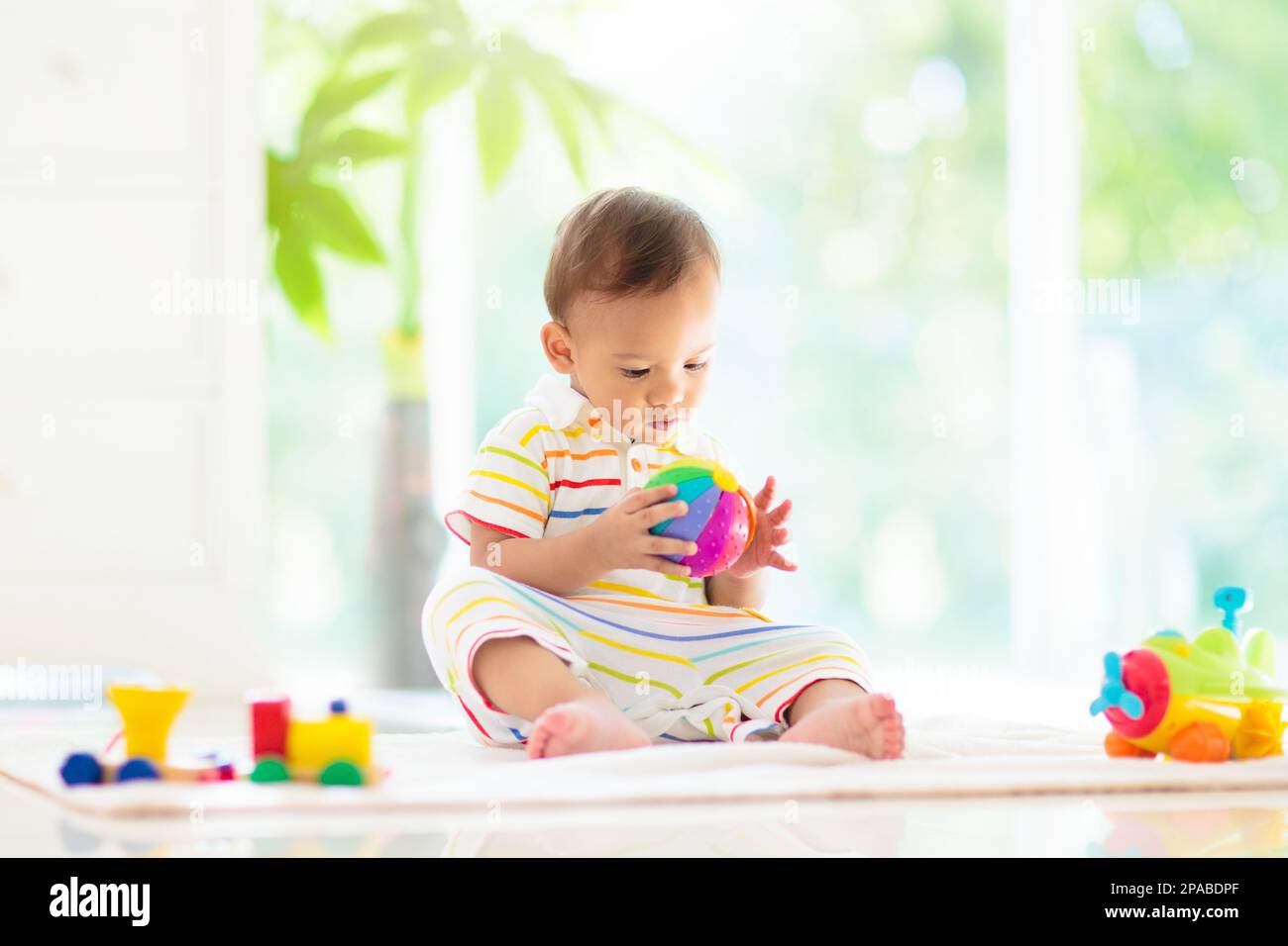 Adorable Asian baby boy learning to crawl and playing with colorful ...