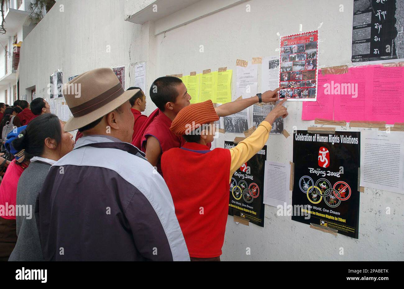Tibetan exiles look at posters with photographs of demonstrations ...