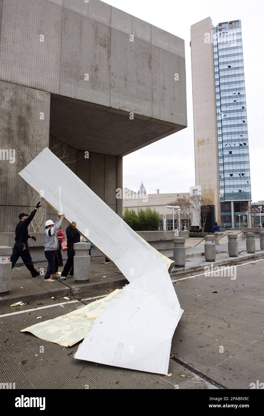Workers move debris ripped from Philips Arena out of the street after a ...
