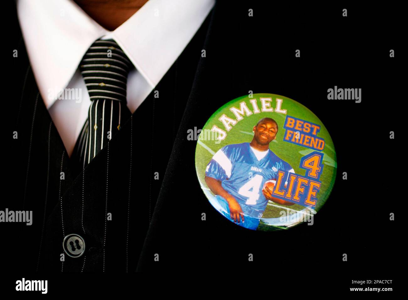 A family member wears a button with the photo of teen football star ...