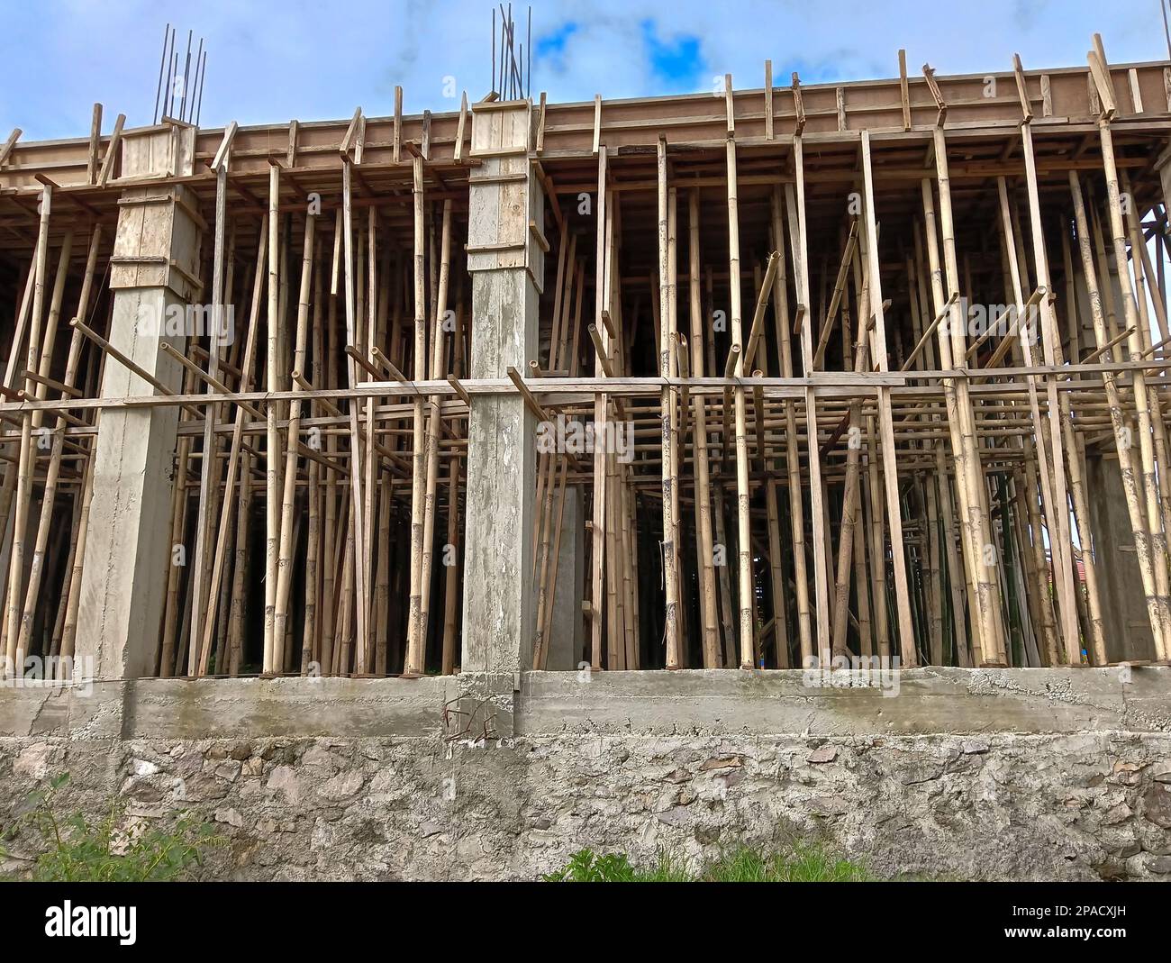 An unfinished building with concrete pillars and bamboo poles as ...