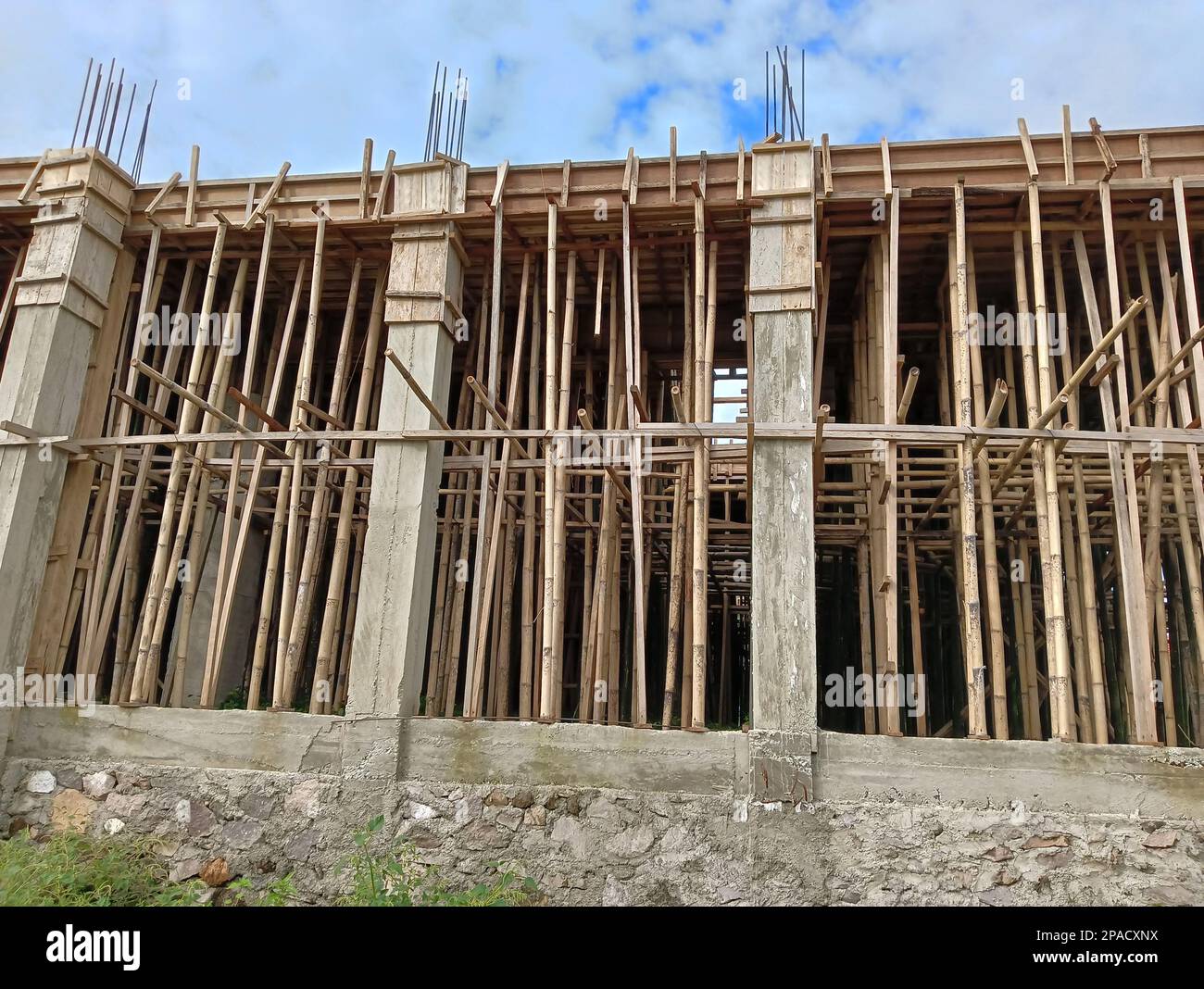 An unfinished building with concrete pillars and bamboo poles as ...