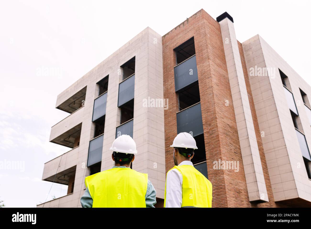 Two architect engineers looking at building construction outdoors Stock ...