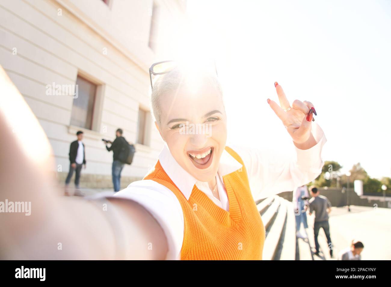 Selfie of young woman looking at camera making peace sign with two ...