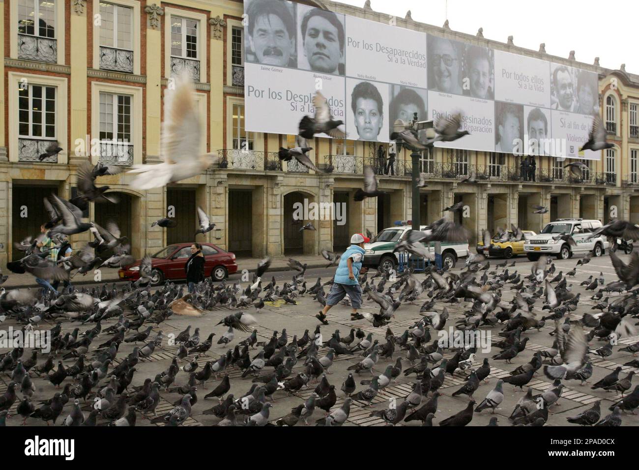 A child runs under a billboard with faces of victims from violence in ...