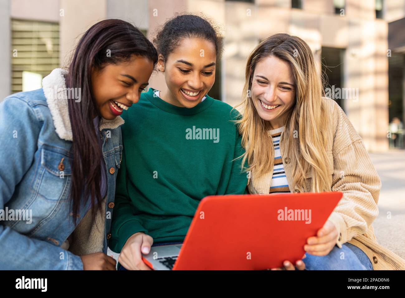 Three young millennial student friends working together on laptop ...