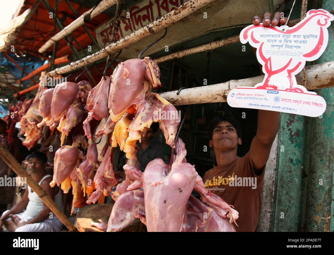 A Bangladeshi butcher adjusts a government notice that reads cooked ...