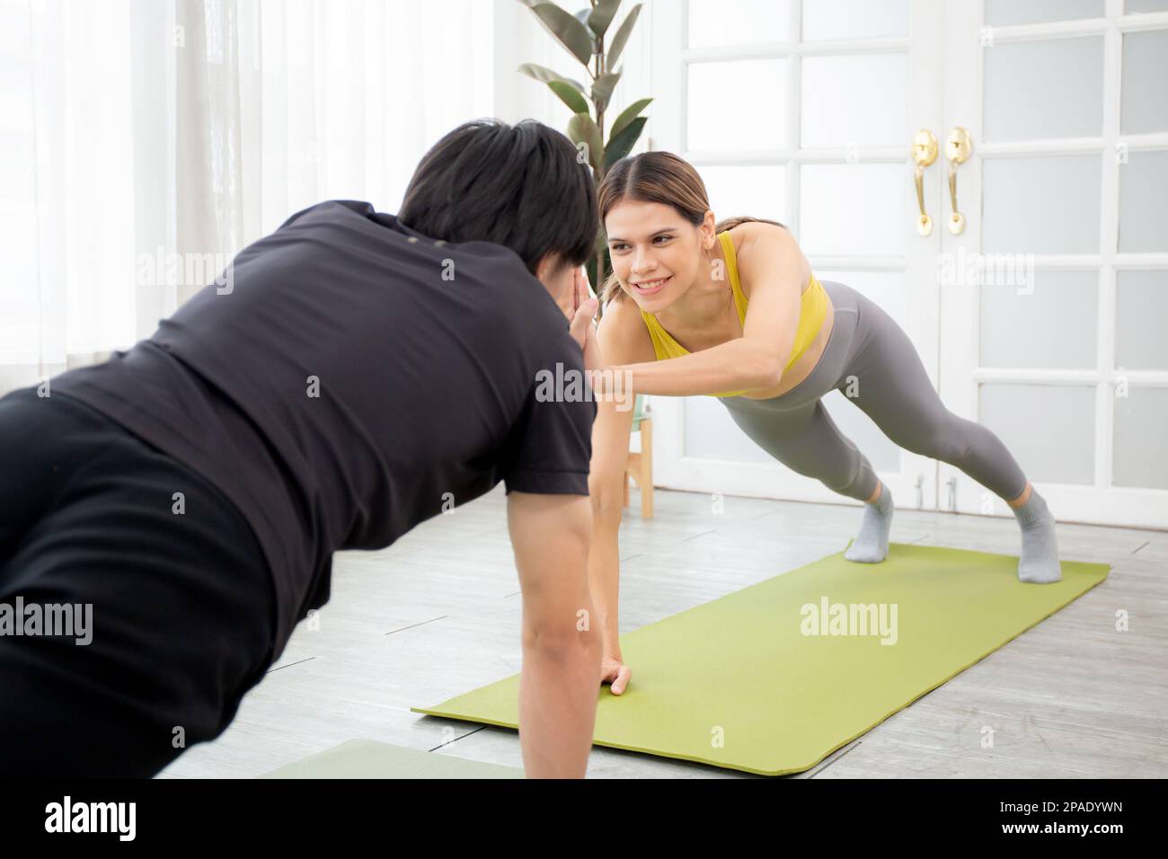 Young woman and man practicing workout with posing plank on mat while ...