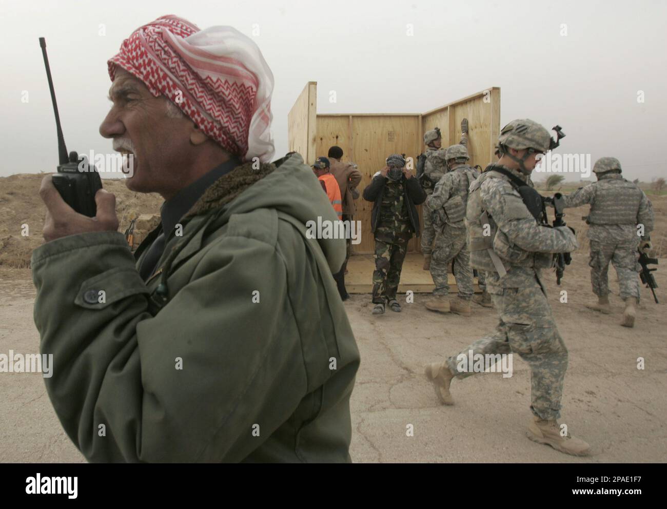 An Iraqi volunteer talks on his radio as US soldiers of Bravo Company ...