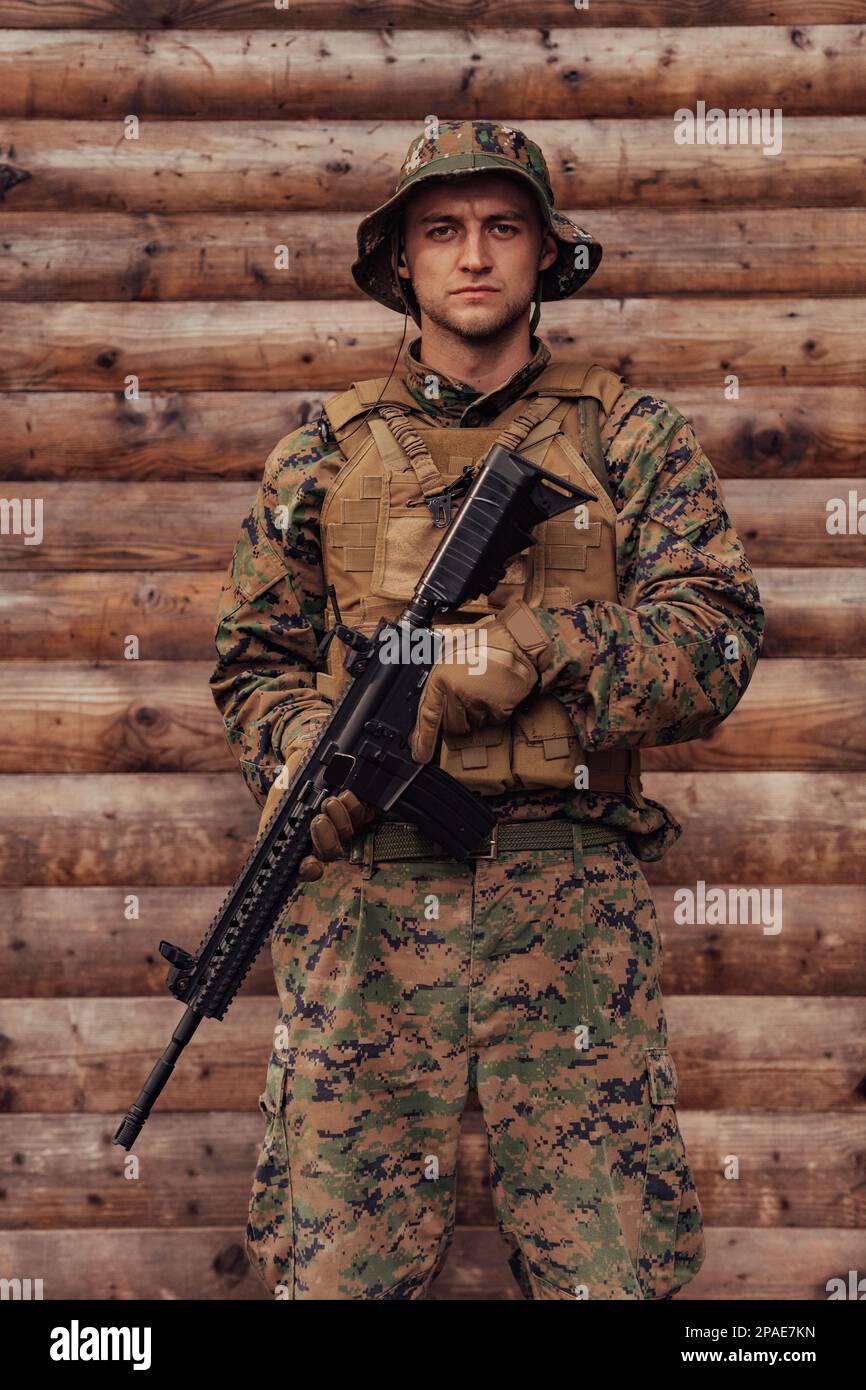A soldier in uniform with a rifle in his hand is standing in front of a ...