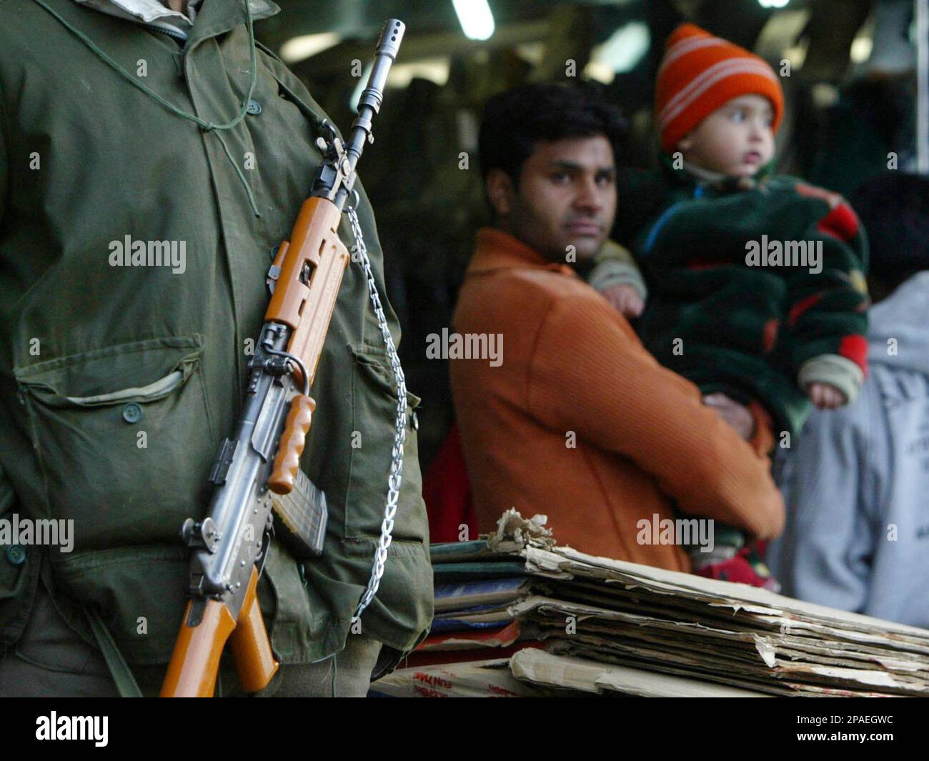 An Indian paramilitary soldier stands guard as a Kashmiri man hold his ...