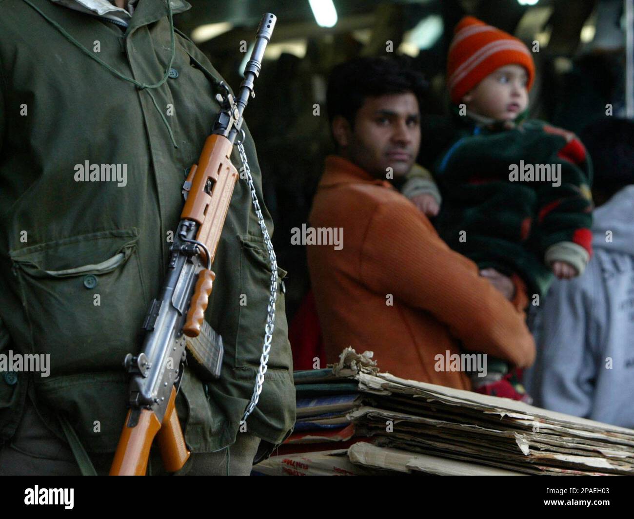 An Indian paramilitary soldier stands guard as a Kashmiri hold his ...