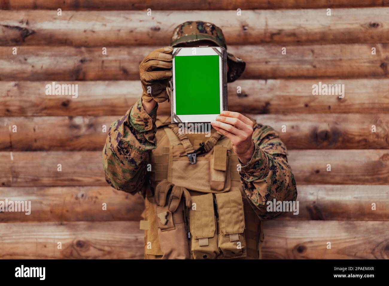 Soldier using tablet computer against old wooden wall in military camp ...