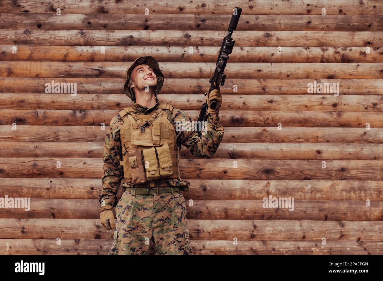 A soldier in uniform with a rifle in his hand is standing in front of a ...