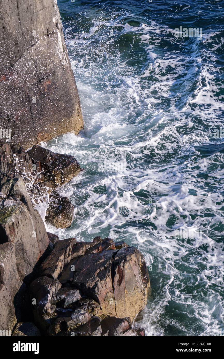Looking down the cliff edge into the waves at the Farne Islands Stock ...